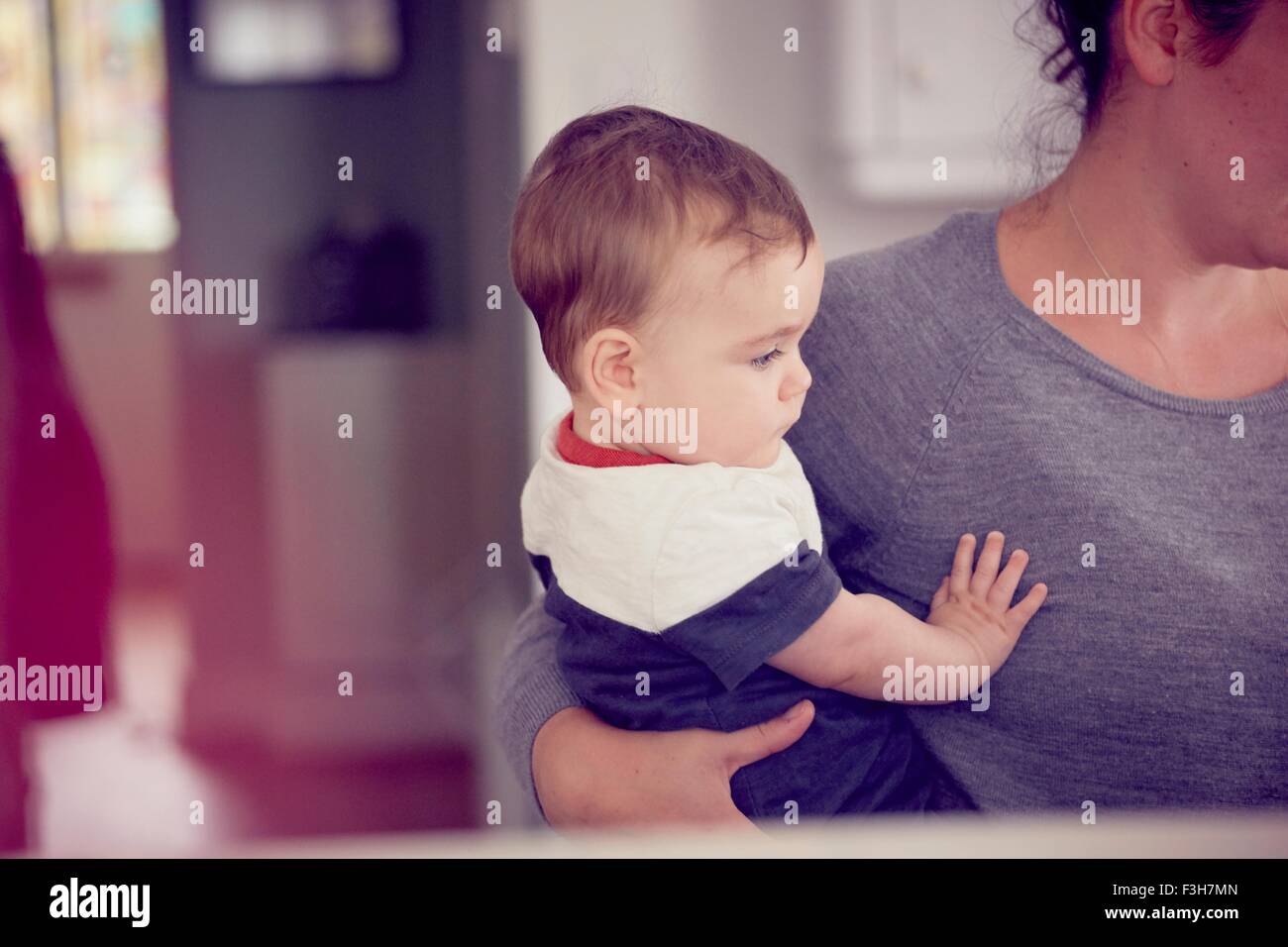 Mother carrying baby boy in kitchen Stock Photo - Alamy