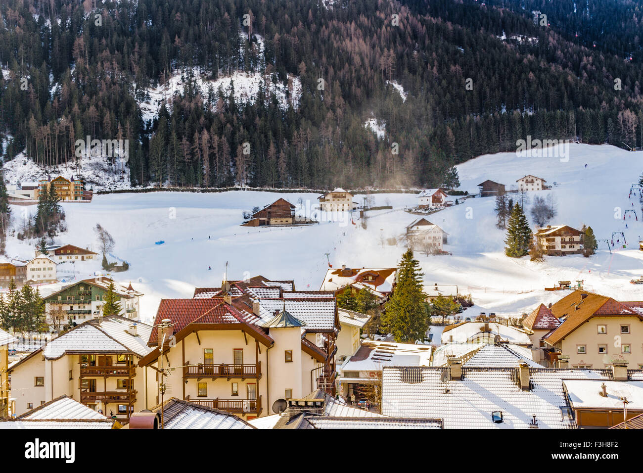 Snowy alpine village in Italy illuminated by sun with mountains in the ...