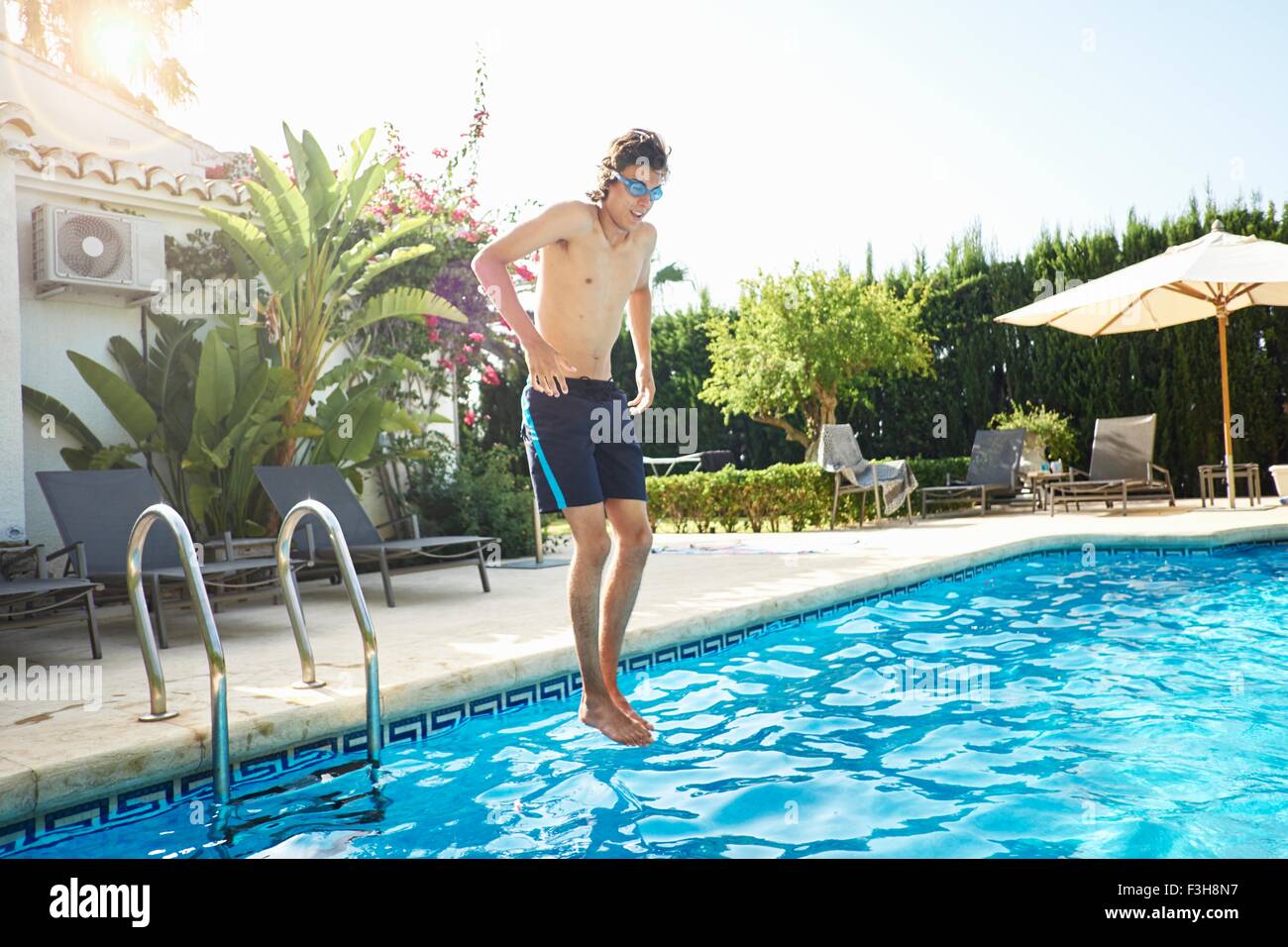 Young man wearing swimming goggles jumping into swimming pool Stock ...