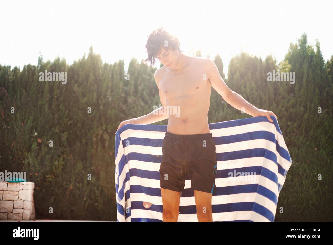 Young man drying himself with towel at poolside Stock Photo - Alamy