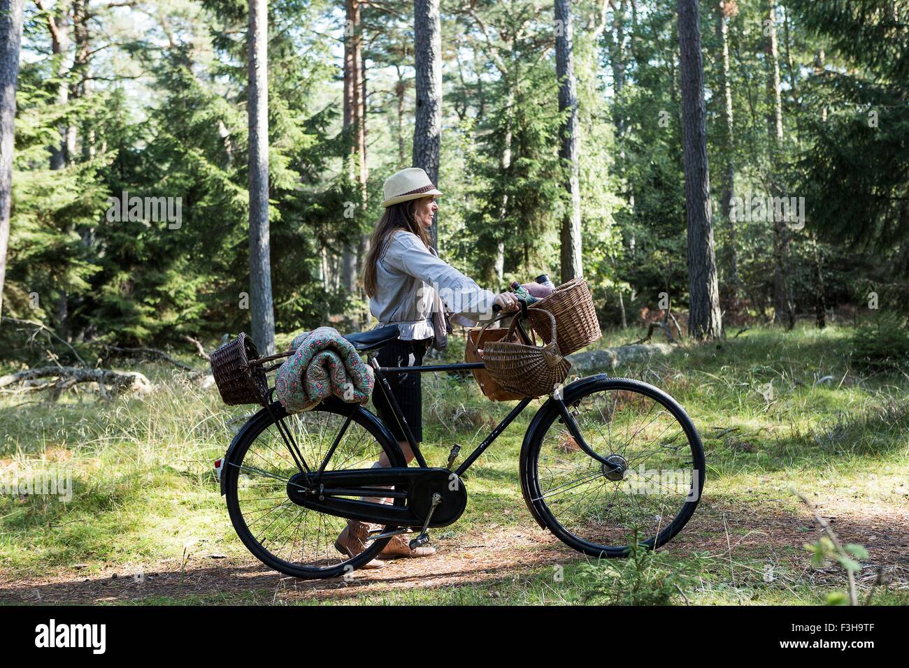 Mature woman cyclist with foraging baskets on forest path Stock Photo ...