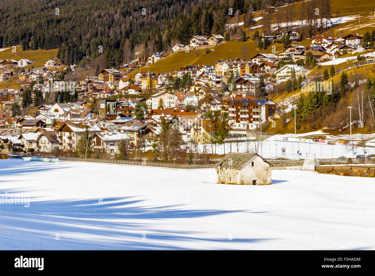 Snowy alpine village in Italy illuminated by sun with mountains in the ...