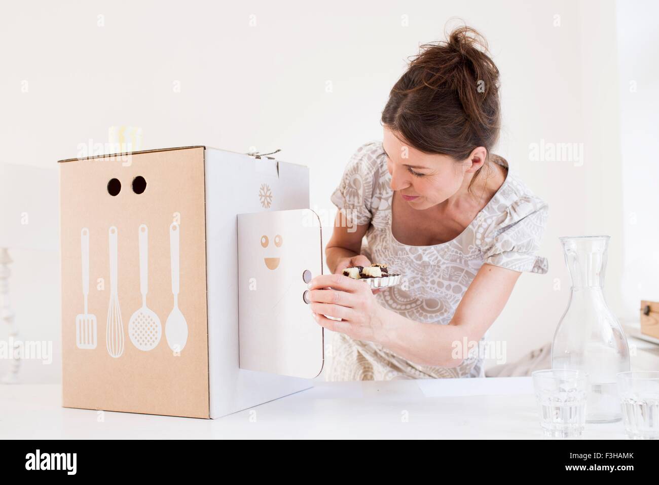 Mature woman holding baked products looking at cardboard box with ...