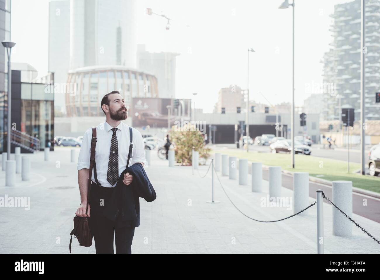 Stylish businessman carrying jacket walking in city Stock Photo - Alamy