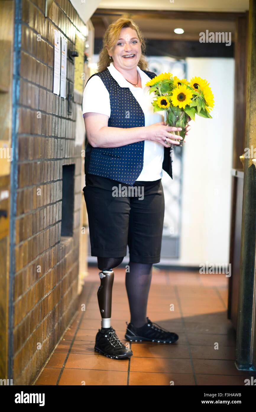 Portrait of mid adult woman with prosthetic leg, standing, holding ...