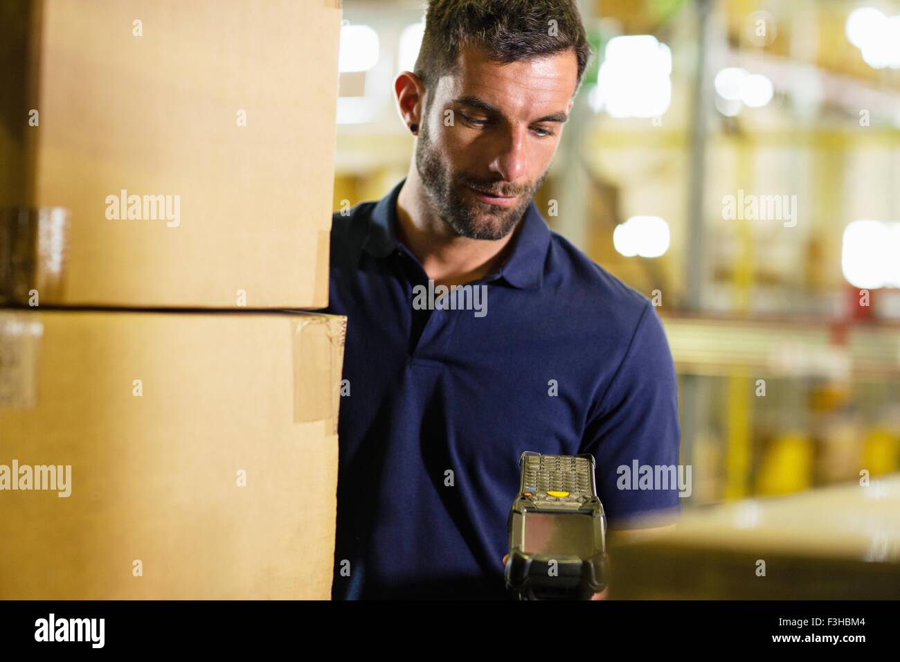 Male warehouse worker using barcode scanner in distribution warehouse ...