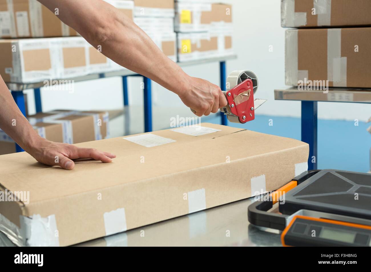 Hands of warehouse worker taping parcel in distribution warehouse Stock ...