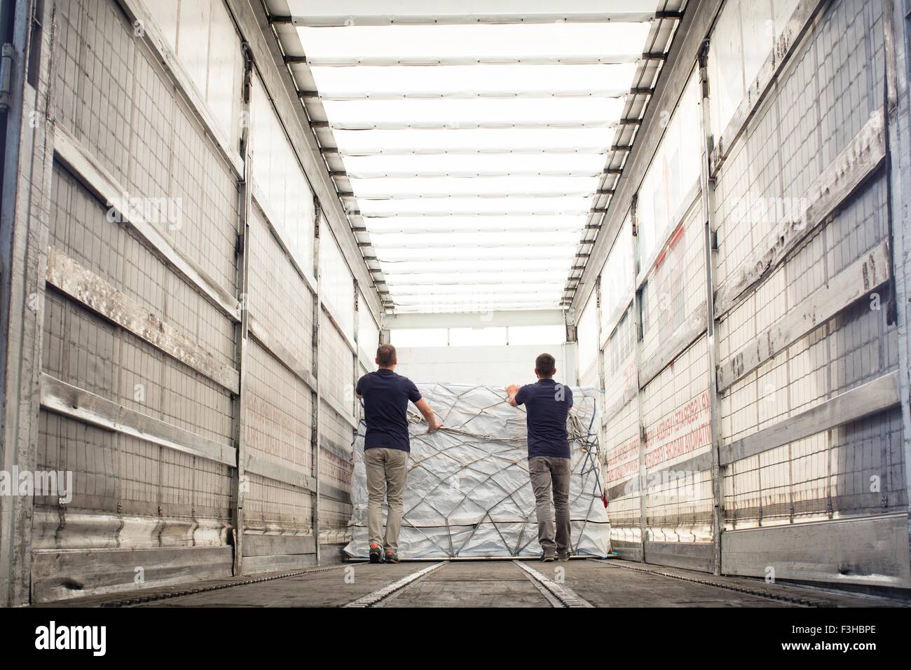 Workers pushing freight in air freight container Stock Photo - Alamy