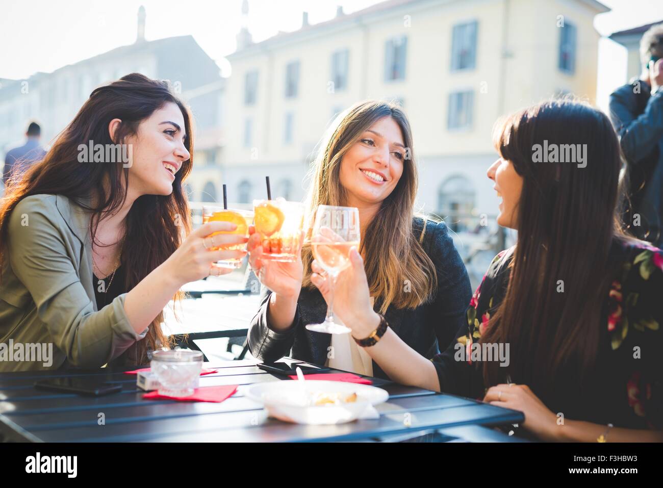 Three young women raising a toast at sidewalk cafe Stock Photo - Alamy