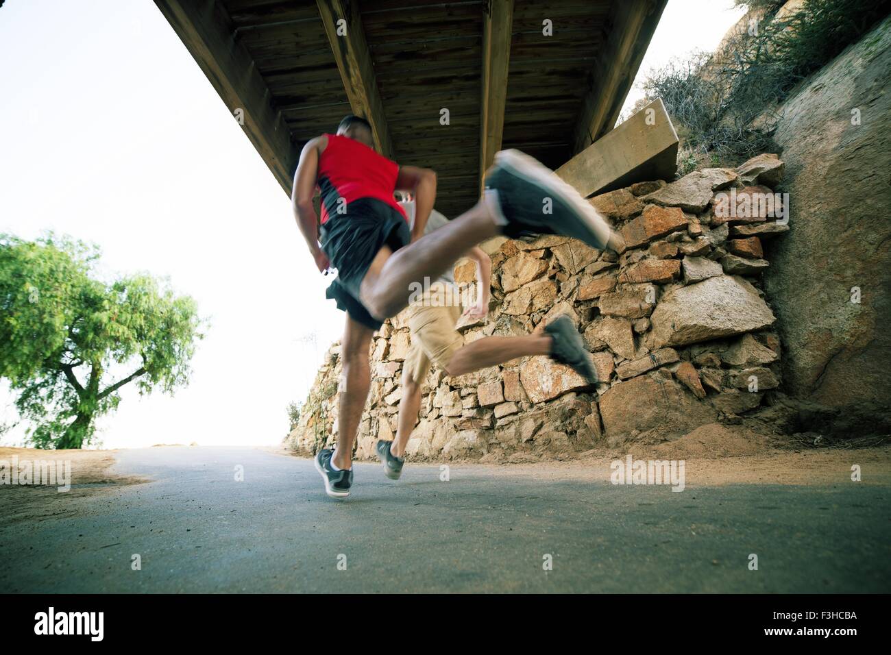 Two male friends, running under bridge, rear view, low angle view Stock ...