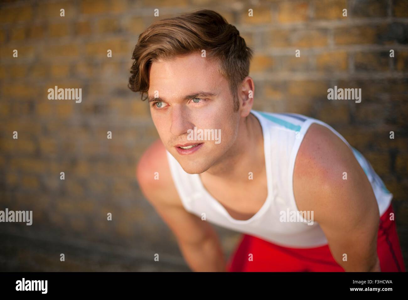 Runner stretching by brick wall Stock Photo - Alamy