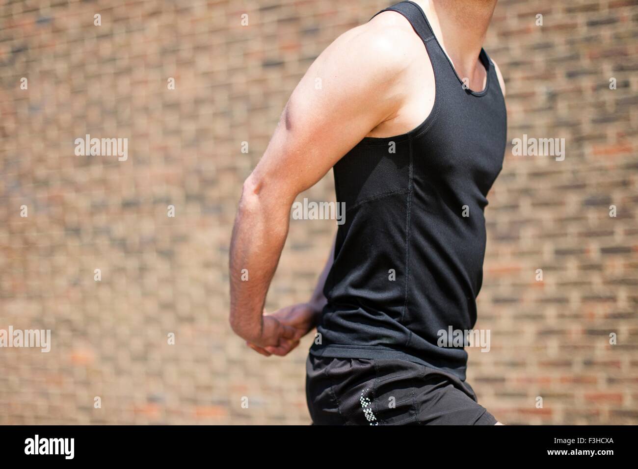 Runner stretching by brick wall Stock Photo - Alamy