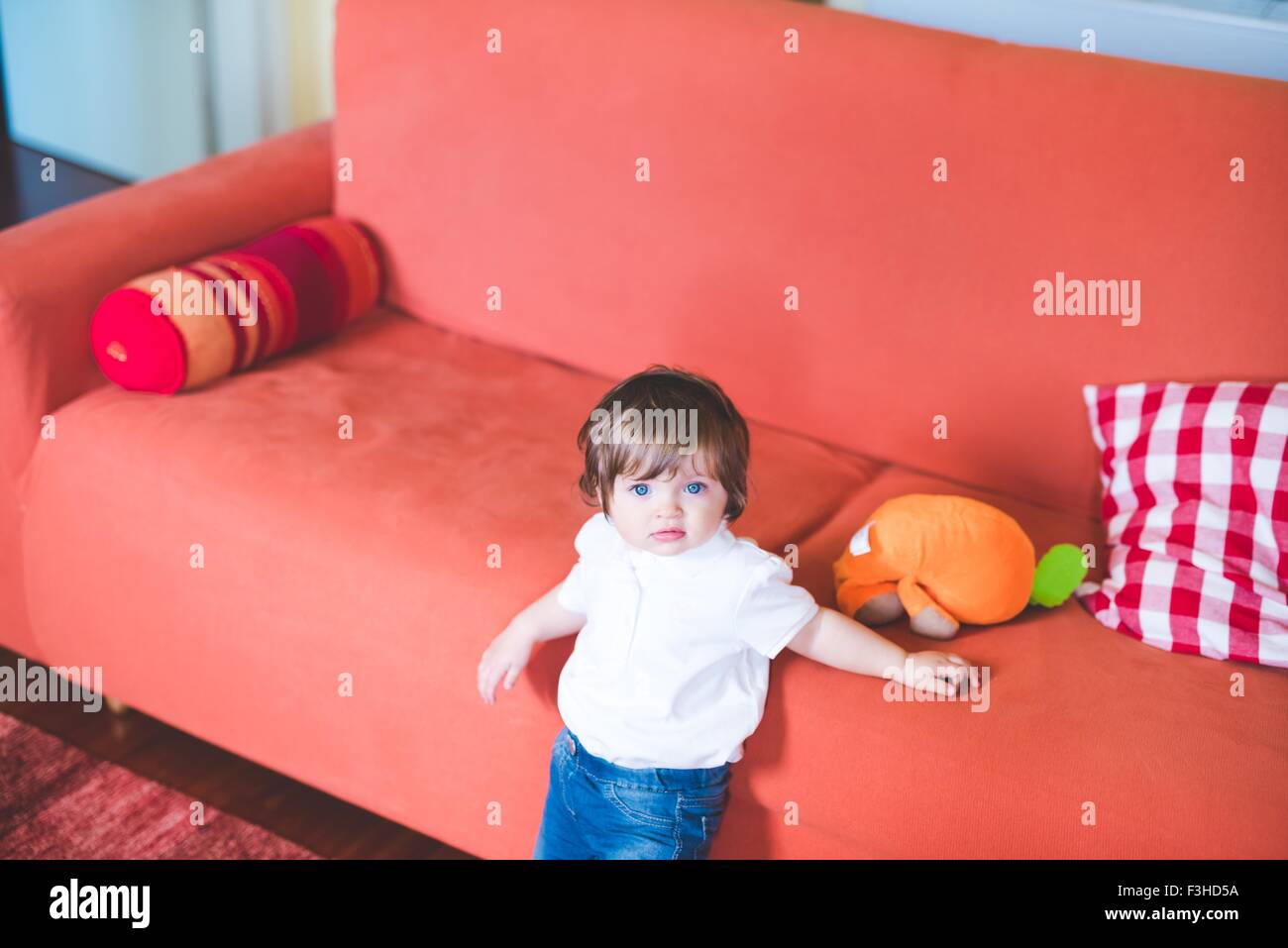 Portrait of female toddler leaning against sofa Stock Photo - Alamy