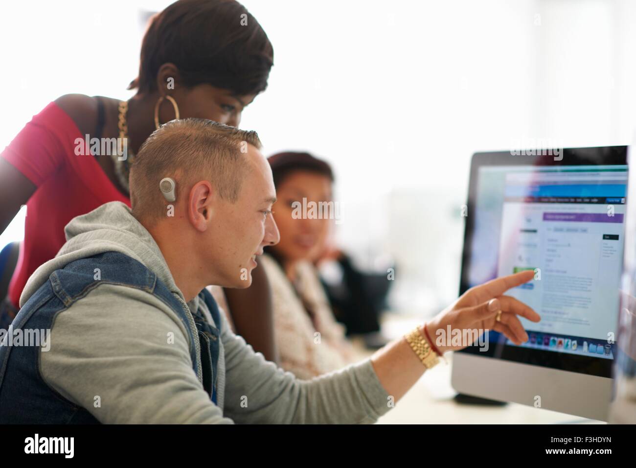 Group of students pointing at desktop computer in classroom Stock Photo ...