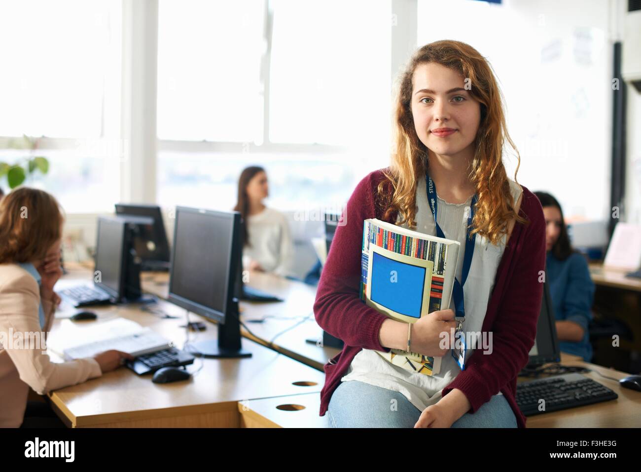 Portrait of female student holding file infront of computer class Stock ...