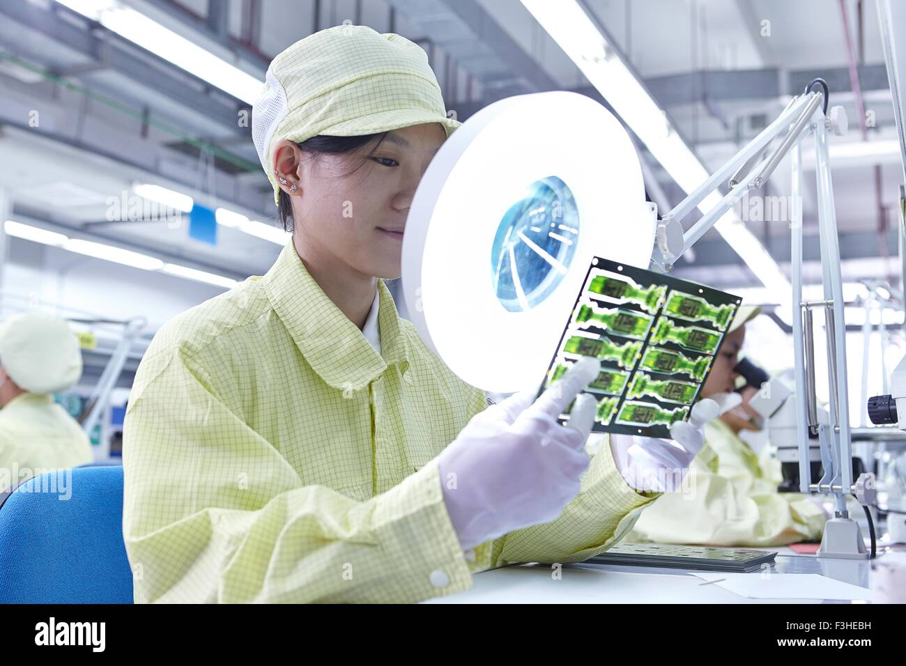 Female worker magnifying glass quality check station factory producing ...