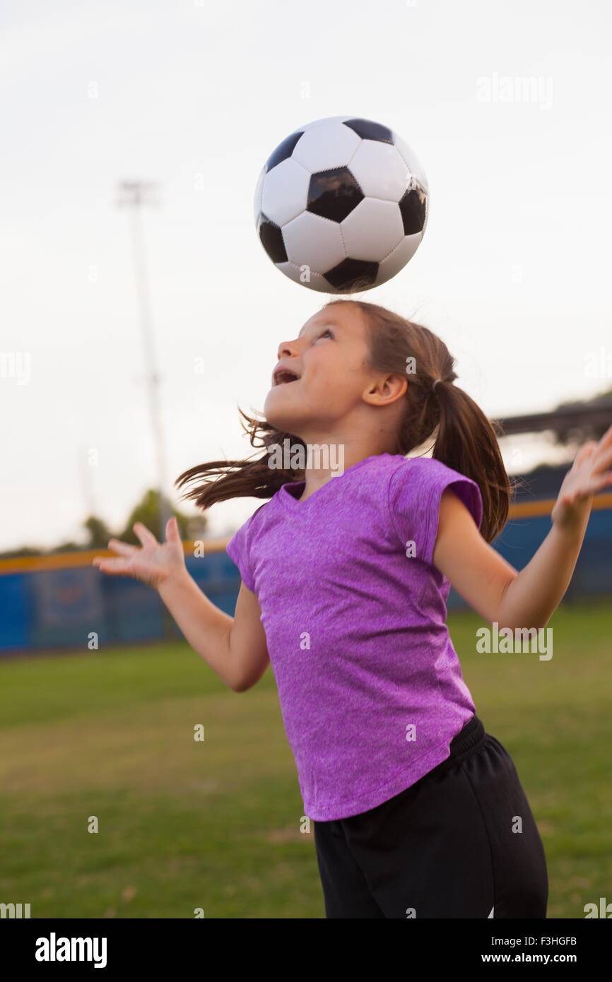 Girl heading football on practice pitch Stock Photo - Alamy