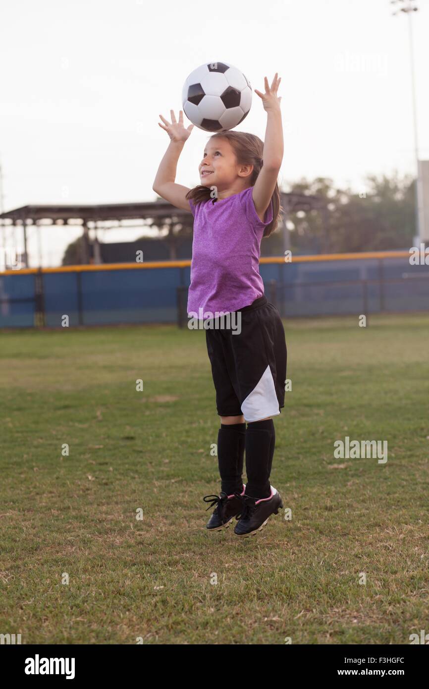 Girl jumping and heading football on practice pitch Stock Photo - Alamy