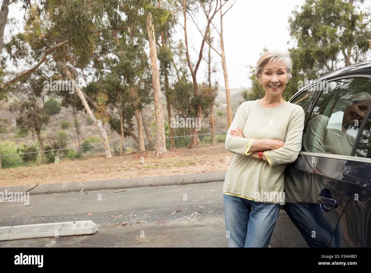 Portrait of senior woman leaning against car Stock Photo - Alamy