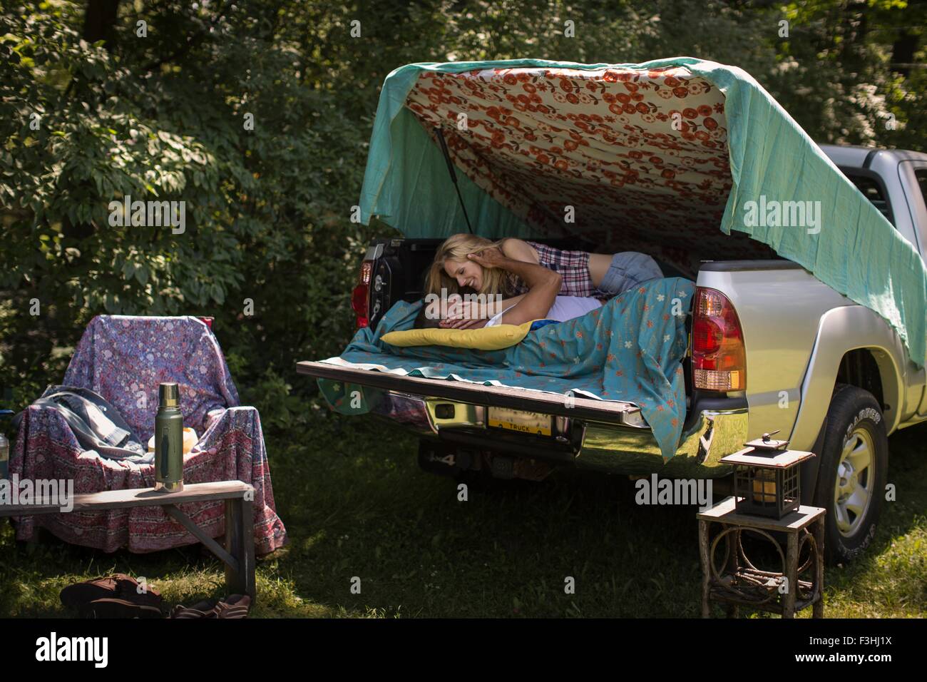 Young woman kissing boyfriend in pick up boot whilst camping Stock ...