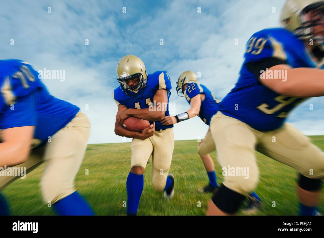 Team of teenage American football players practicing on playing field ...