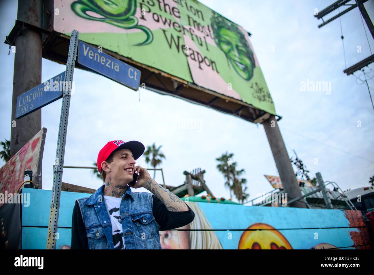 Graffiti artist using smartphone under street signs, Venice Beach ...
