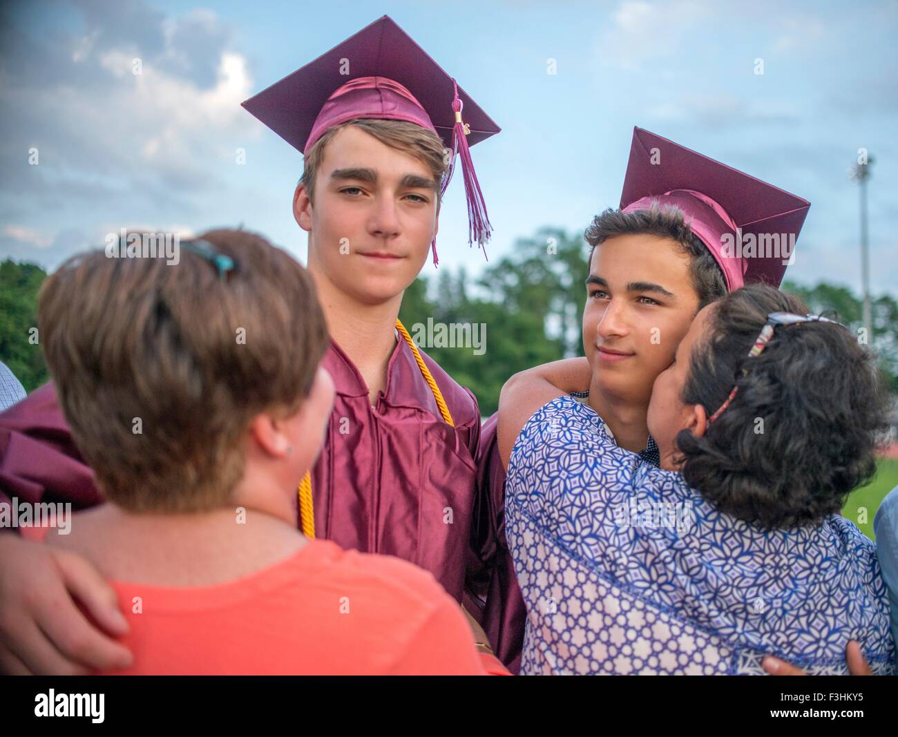 Two young men hugging family at graduation ceremony Stock Photo - Alamy