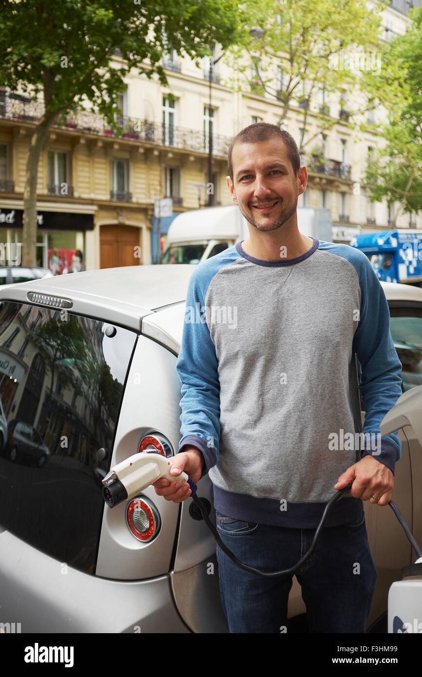 Man charging electric car on street, Paris, France Stock Photo - Alamy