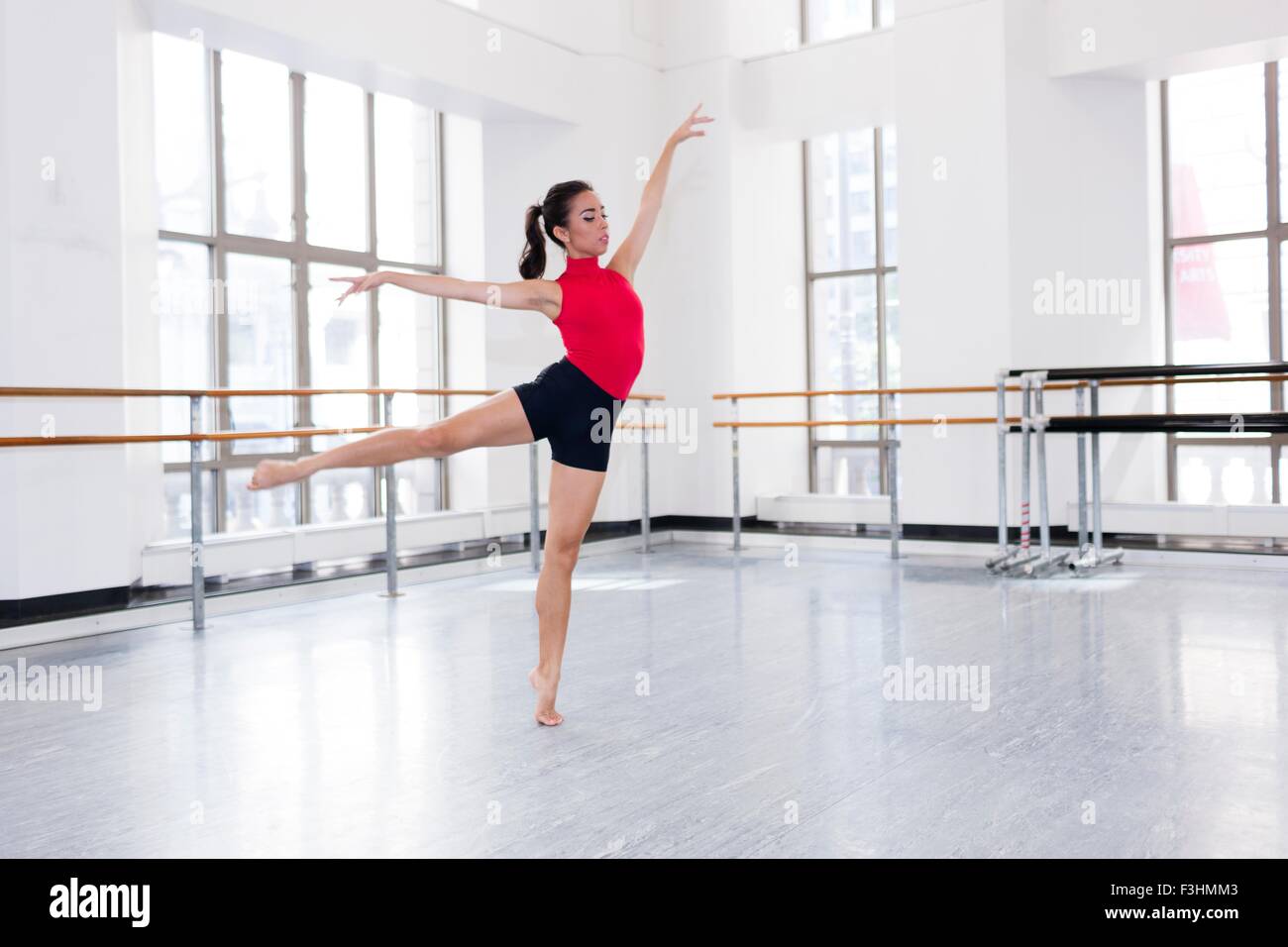 Young woman in dance studio dancing, arms and leg raised Stock Photo ...
