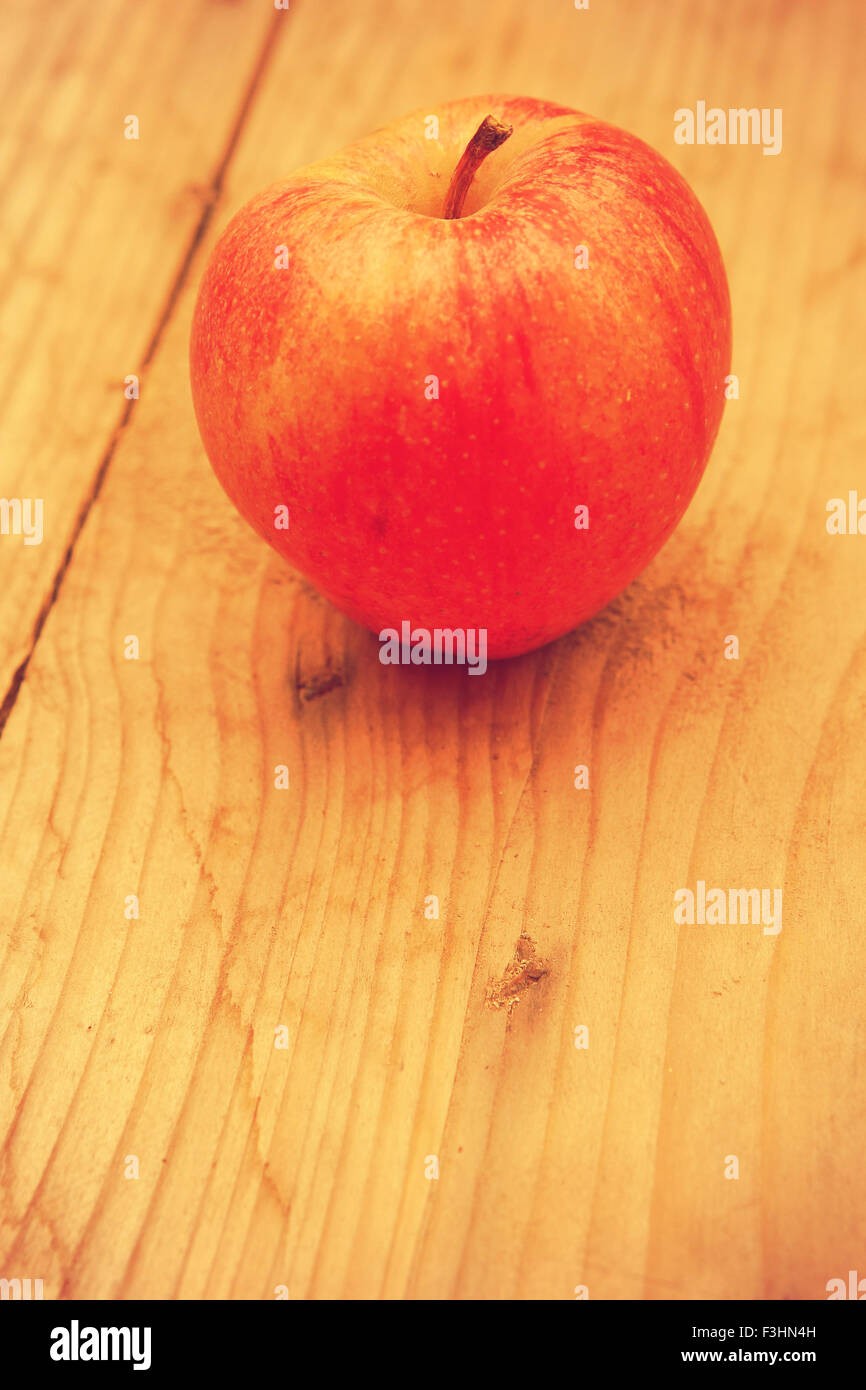 Red apple on a wooden table.Vintage effect Stock Photo - Alamy