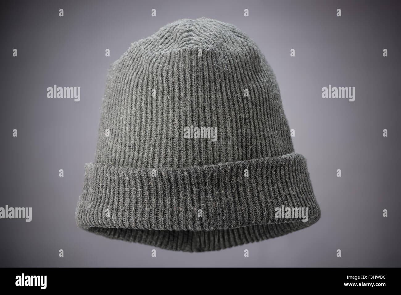 A studio shot of a grey knit cap suspended on a grey background lit ...