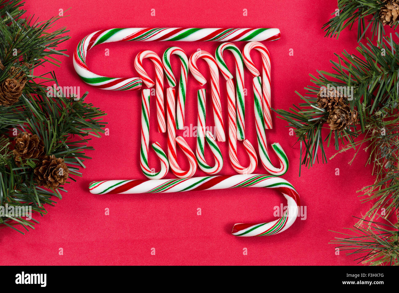 Peppermint candy canes with evergreen branches as side borders on red ...