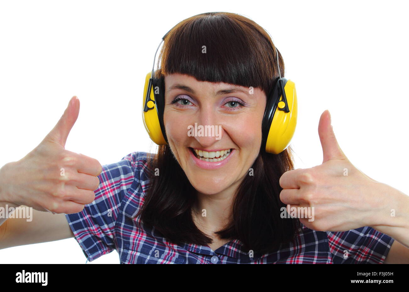 Female construction worker wearing protective headphones and showing thumbs up, safety at work ...