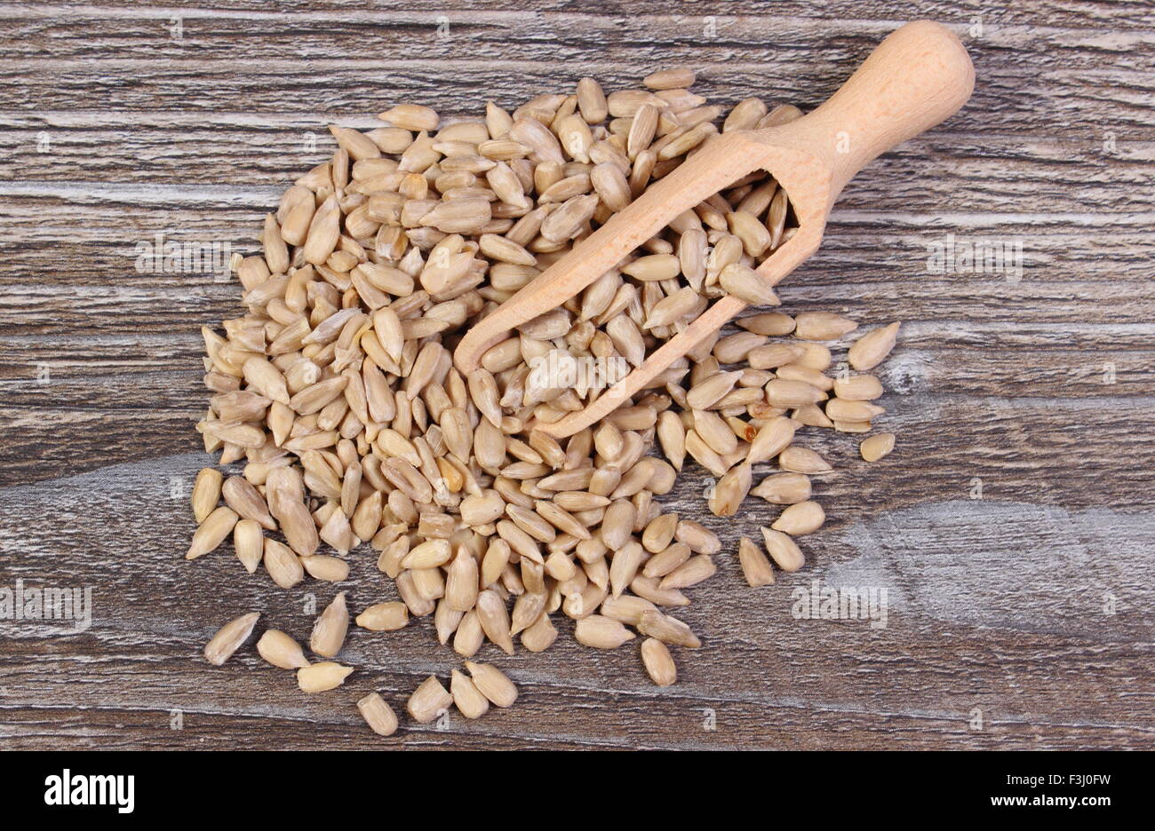 Heap of sunflower seeds with wooden spoon on wooden background, concept ...
