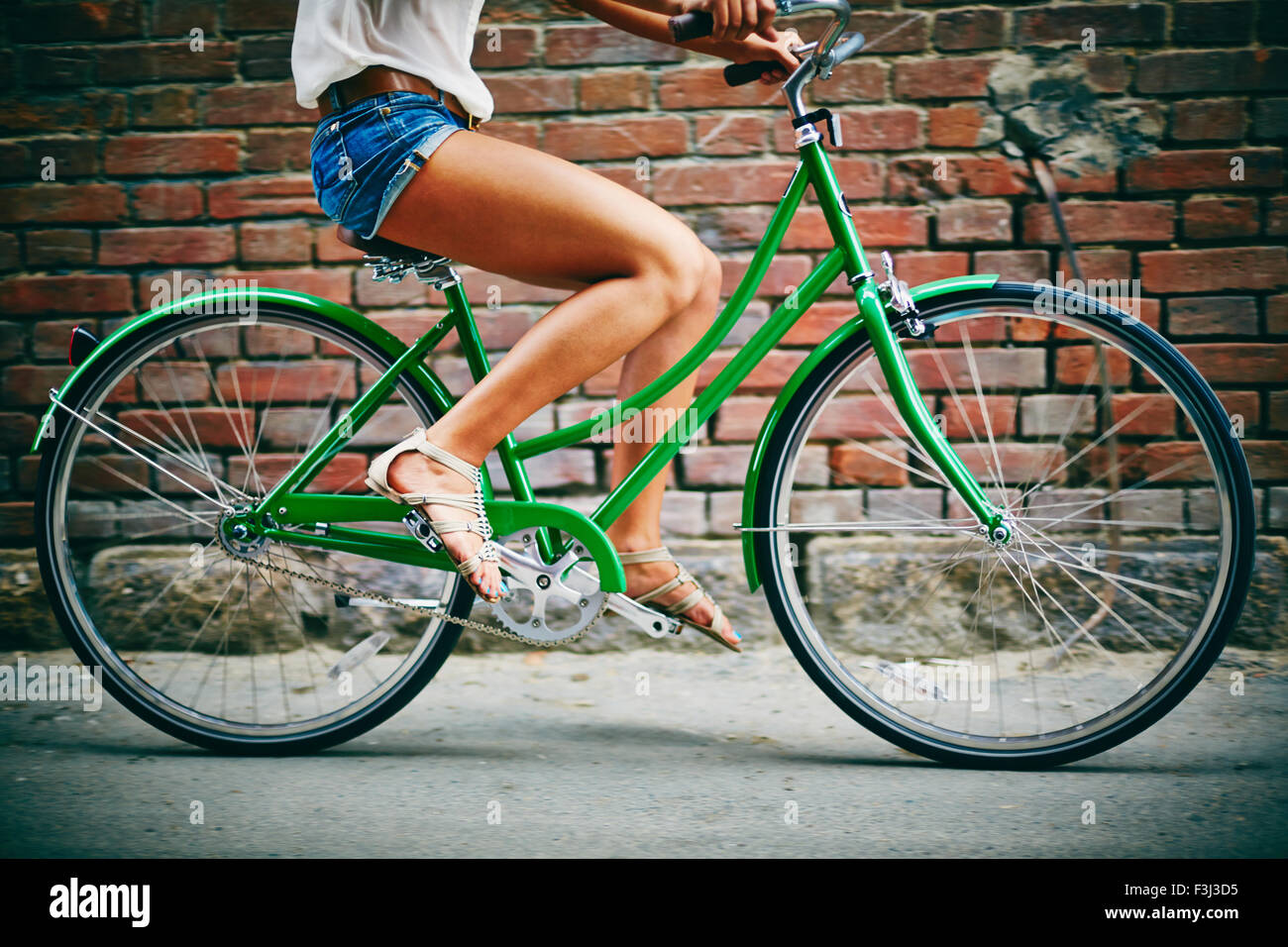 Legs of female bicyclist riding on background of brick wall Stock Photo ...