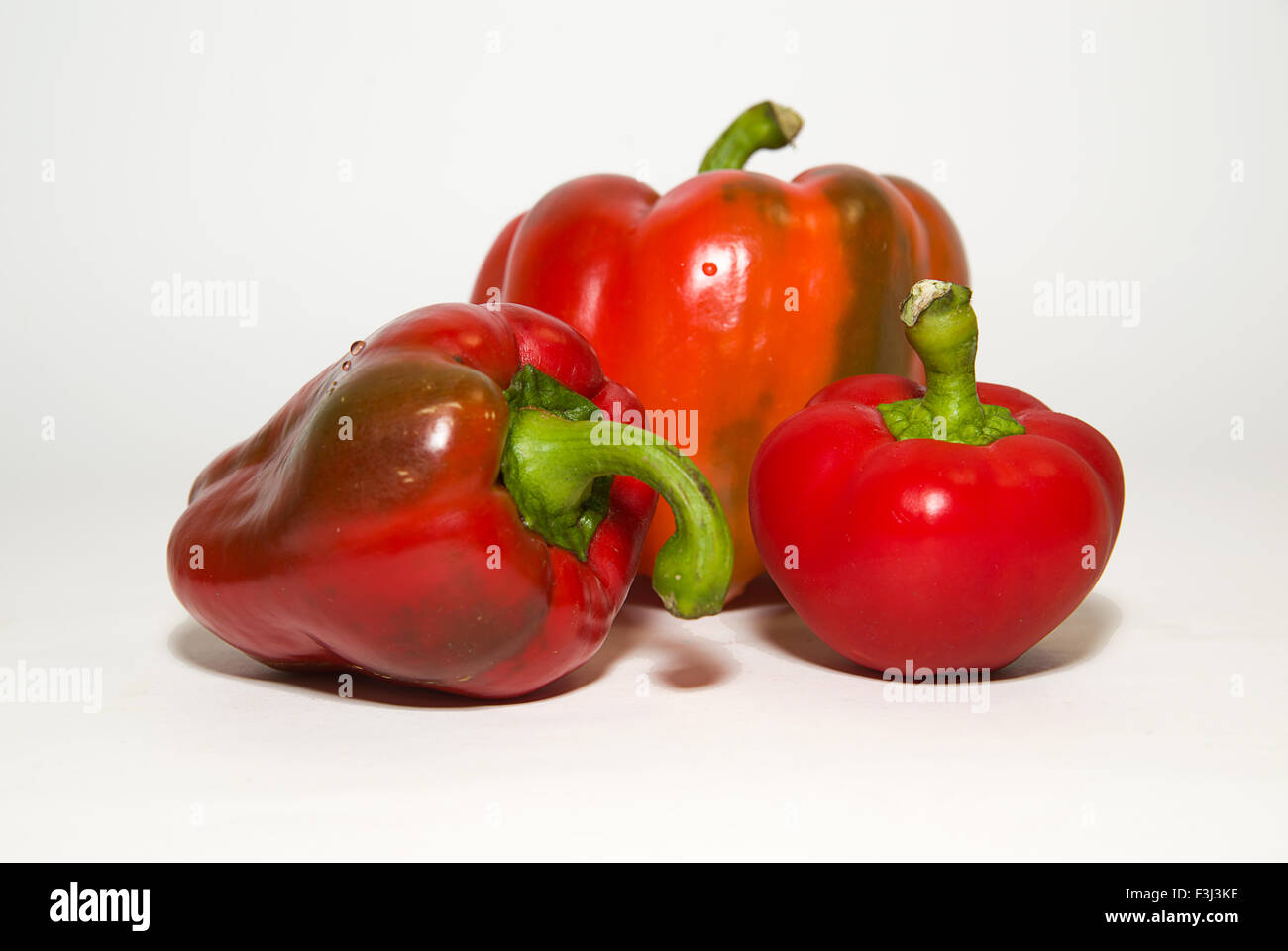 Three red peppers on a white background Stock Photo - Alamy