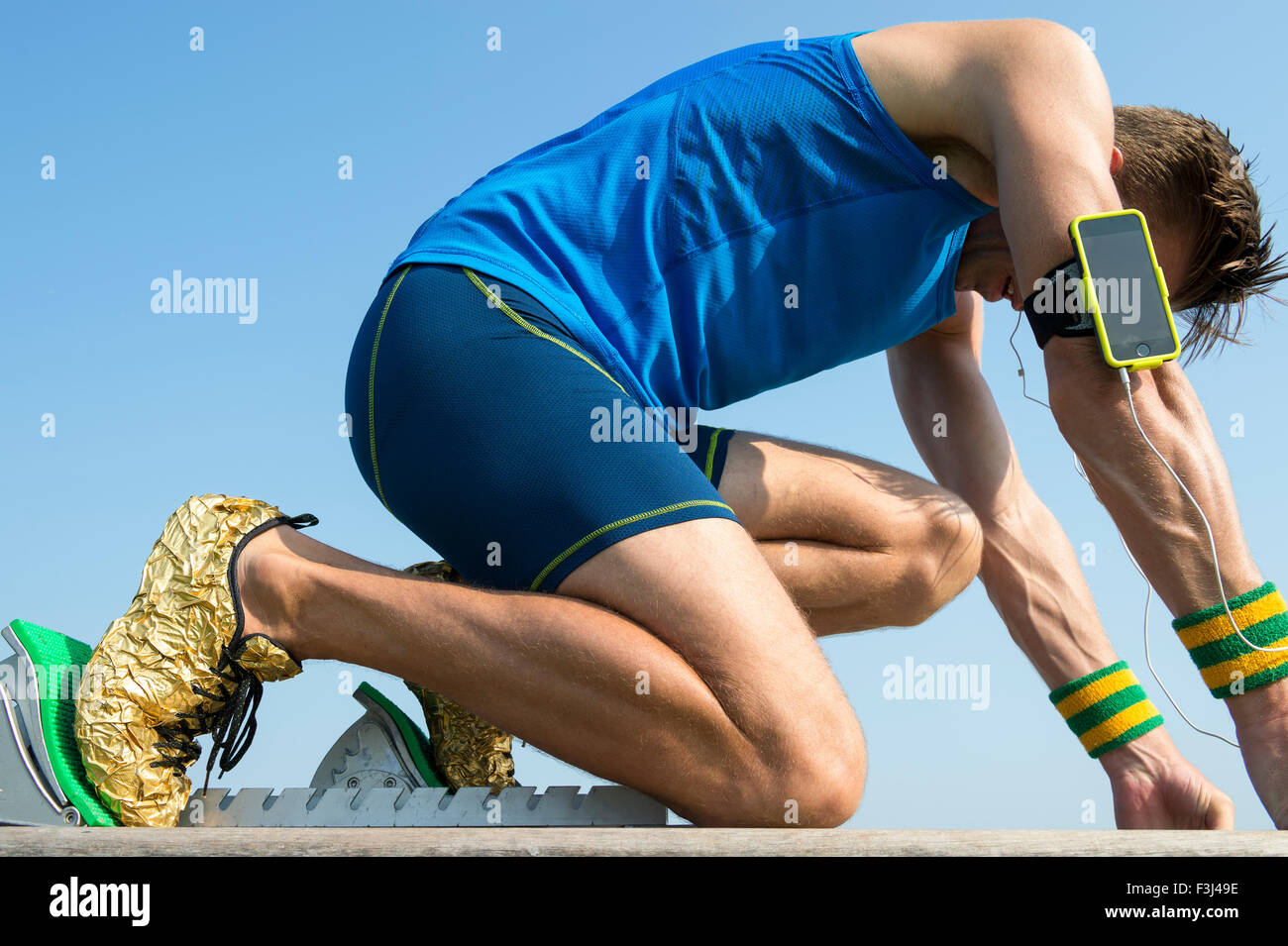 Athlete crouching at the starting line of a running track wearing ...
