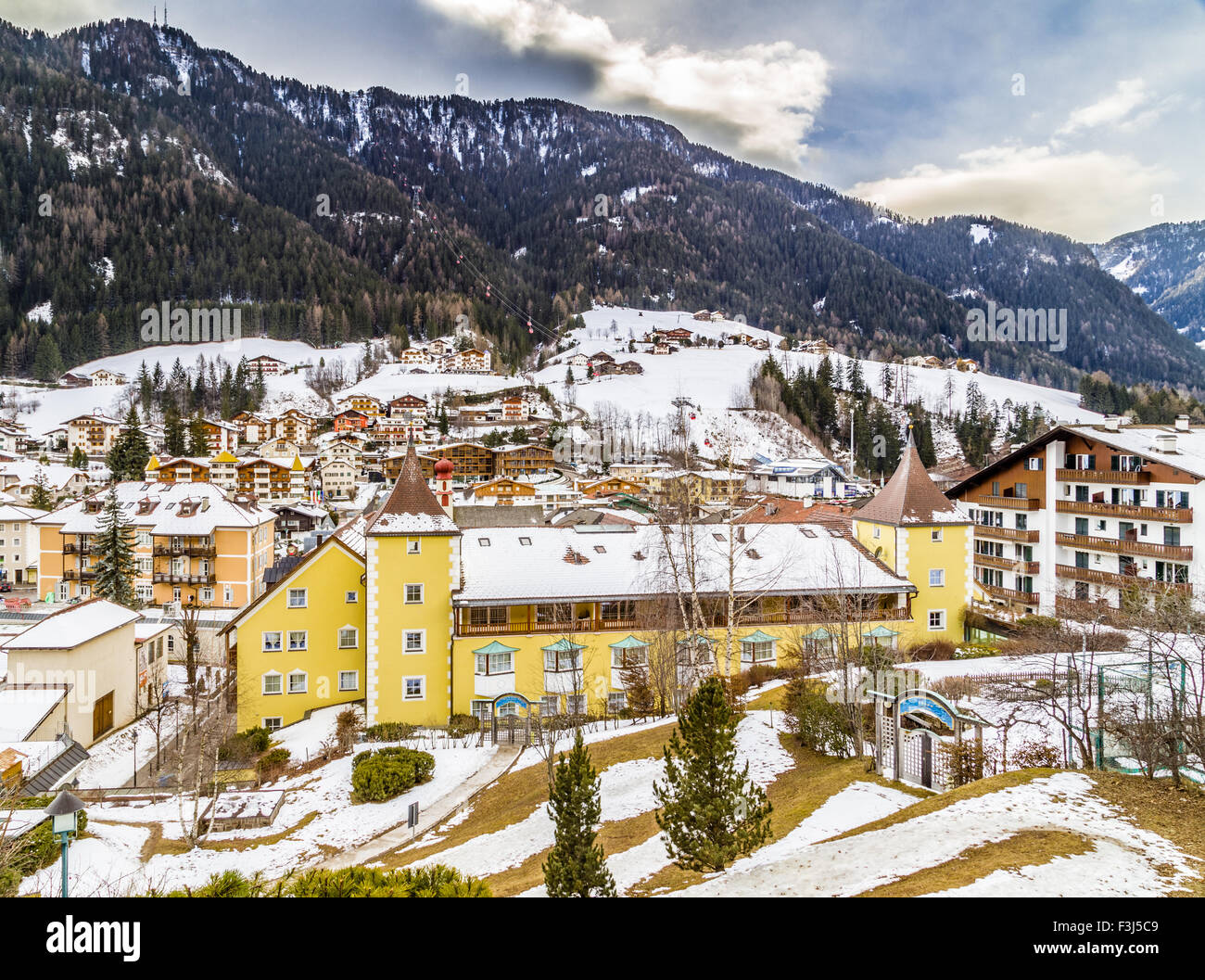 Snowy alpine village in Italy illuminated by sun with mountains in the ...