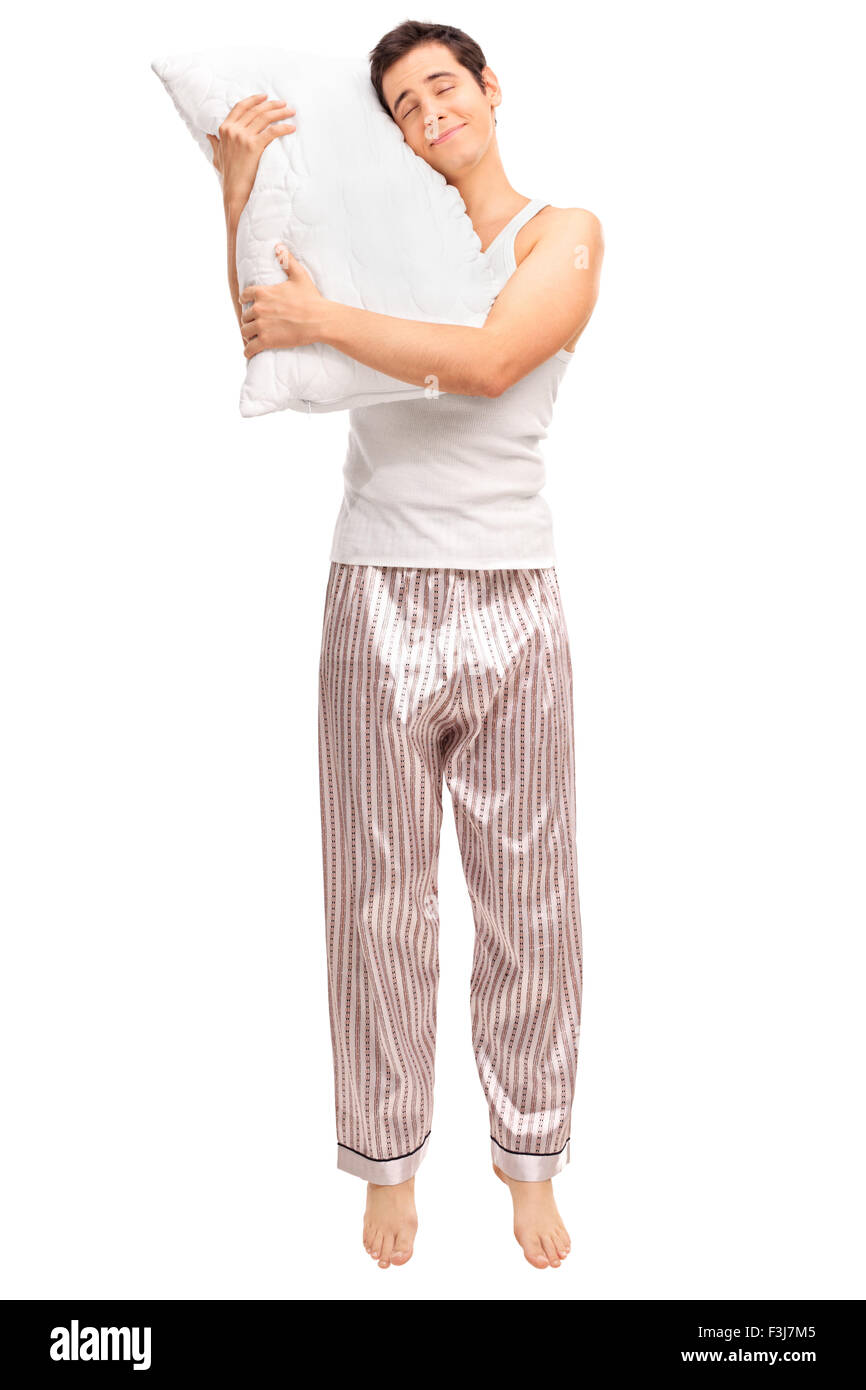 Full length portrait of a joyful young man sleeping while hugging a ...