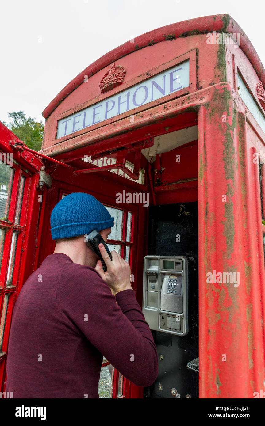 Man using the traditional British red telephone box in a remote ...