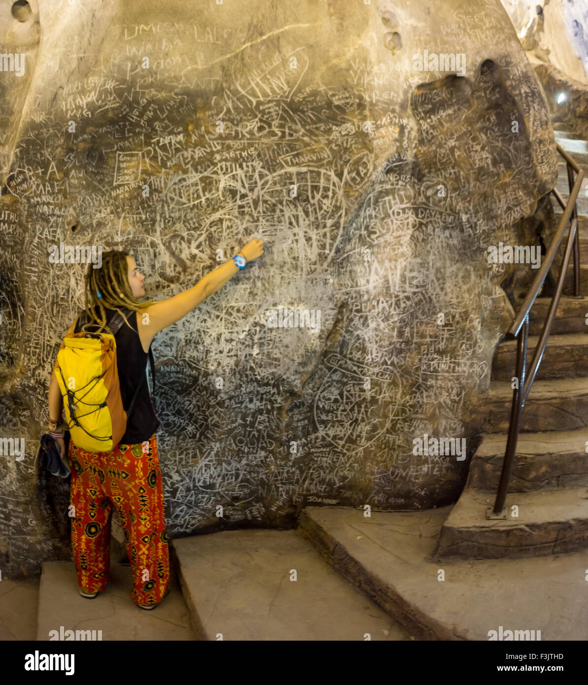 Young woman with backpack exploring cave with torch Stock Photo - Alamy