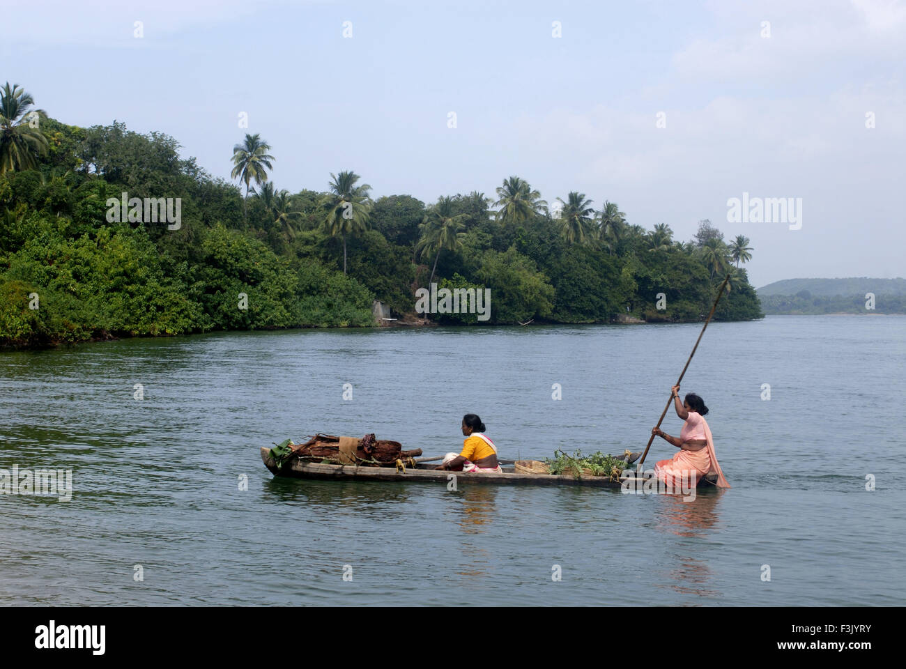 village women in rowing boat ore crossing backwaters of River Karli at ...