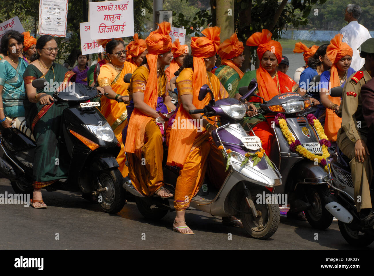 Procession of women wearing traditional dress riding on two wheelers ...