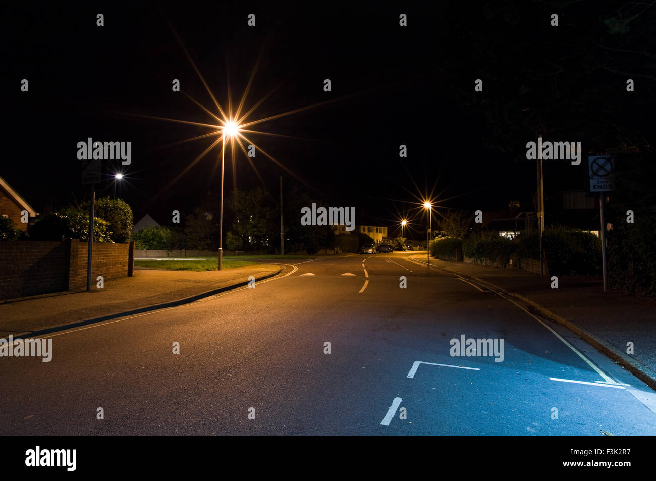 A residential road lit by streetlights at night Stock Photo - Alamy