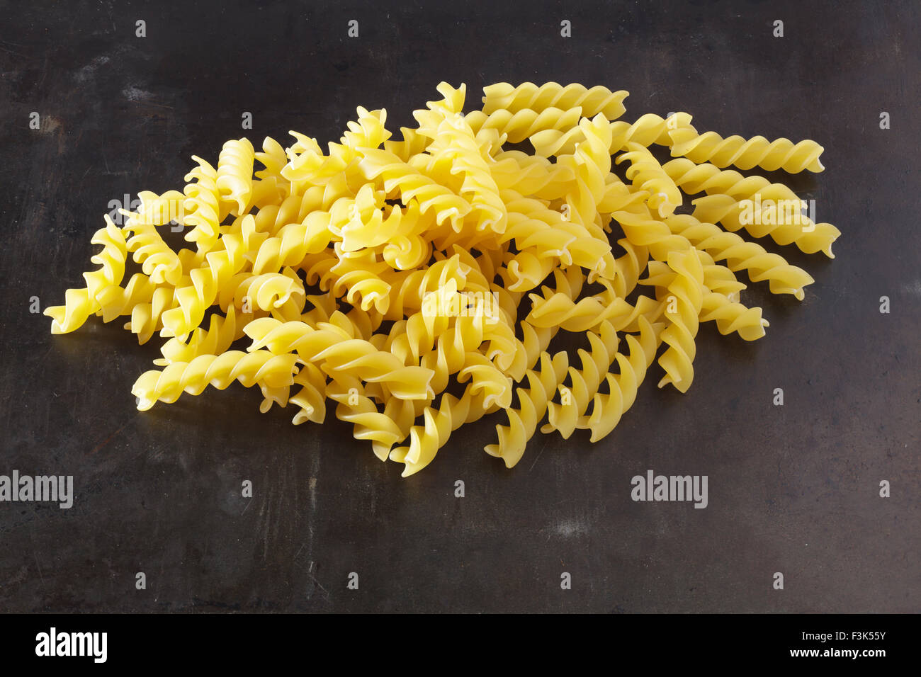Fusilli pasta spirals on dark surface Stock Photo - Alamy