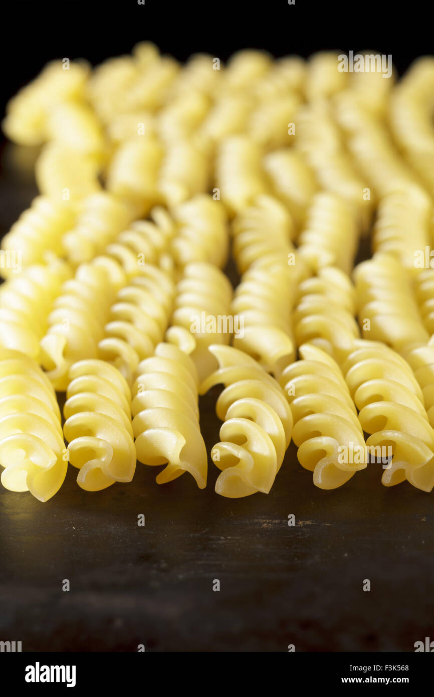 Fusilli pasta spirals on dark surface Stock Photo - Alamy