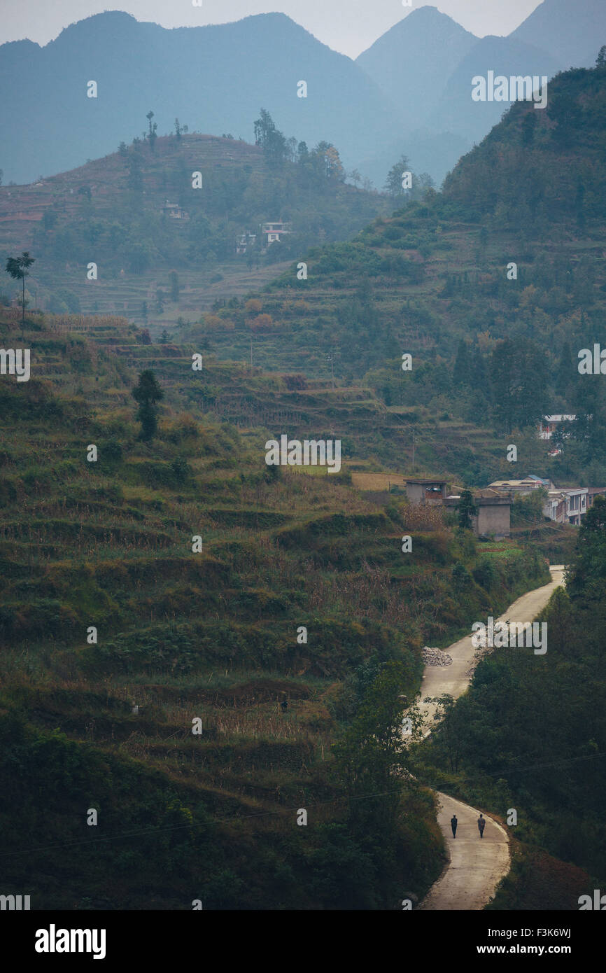 View in from a hill in Southern China. Men walking along village road ...