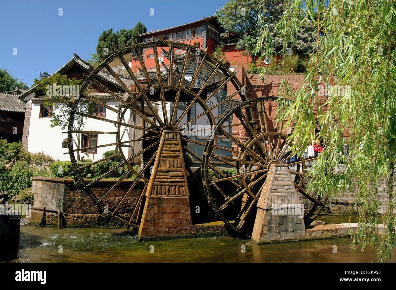 Lijiang, China: Two traditional Chinese wooden water wheels churn water ...