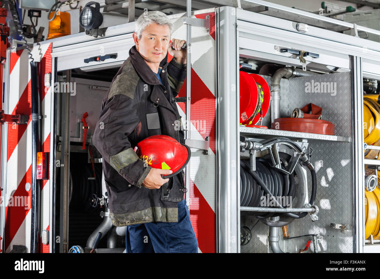 Confident Fireman Standing On Fire Engine Stock Photo - Alamy