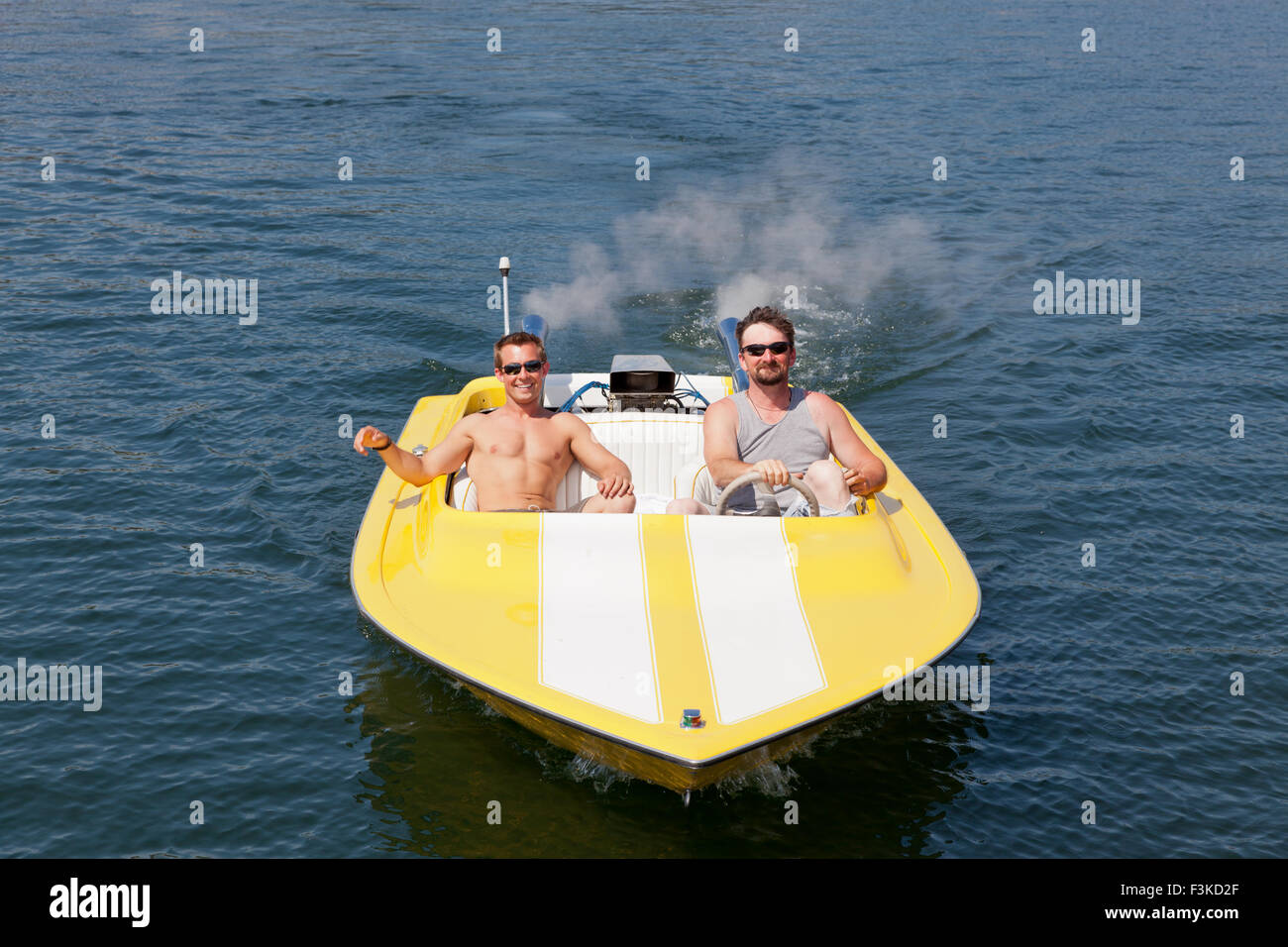 Two smiling men in a yellow and white speedboat having fun in the ...